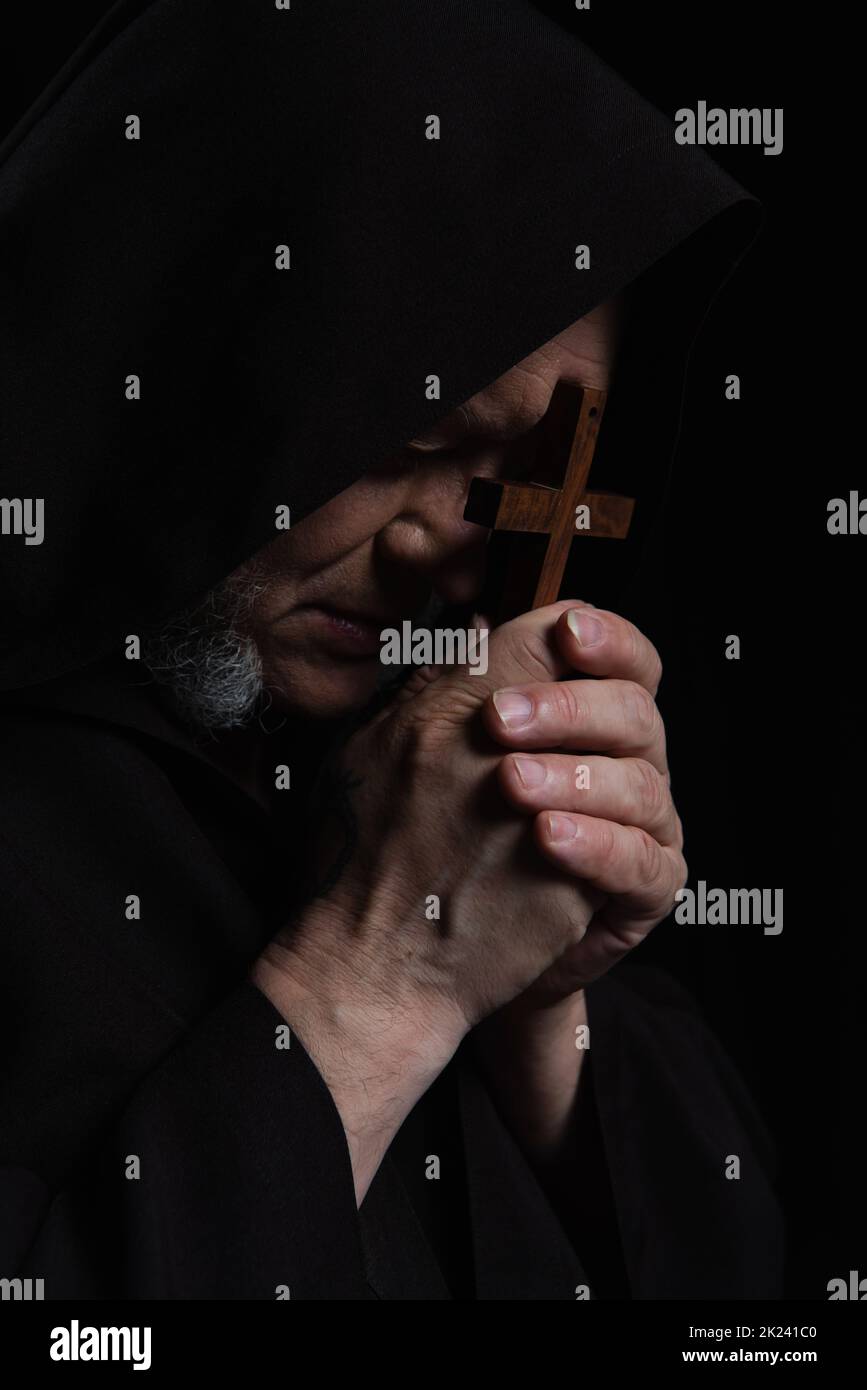 mysterious priest in hood obscuring face with crucifix while praying ...