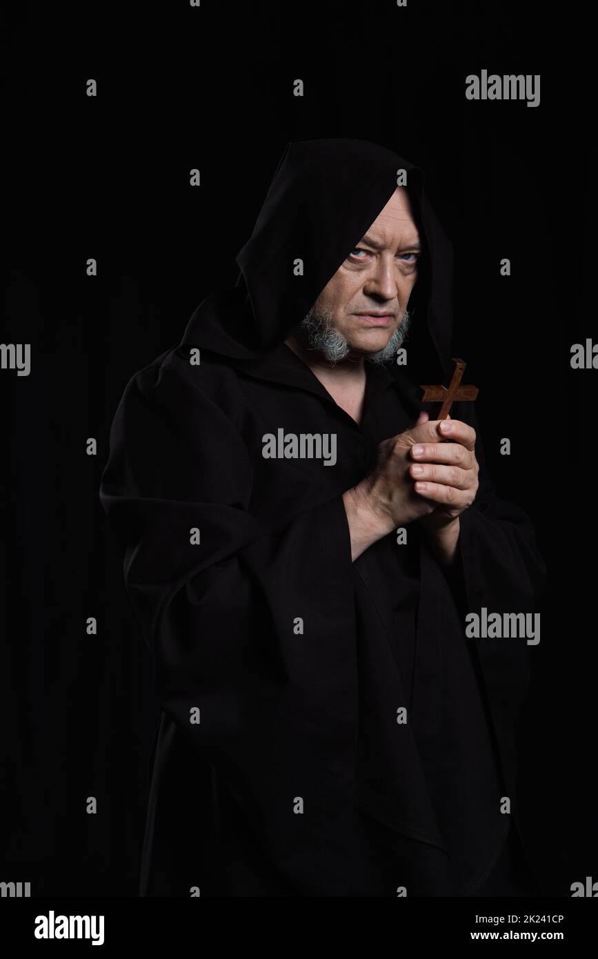 medieval monk in hooded robe holding crucifix and looking at camera ...