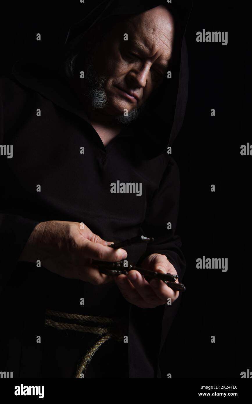 medieval monk in hooded cassock holding keys isolated on black,stock ...