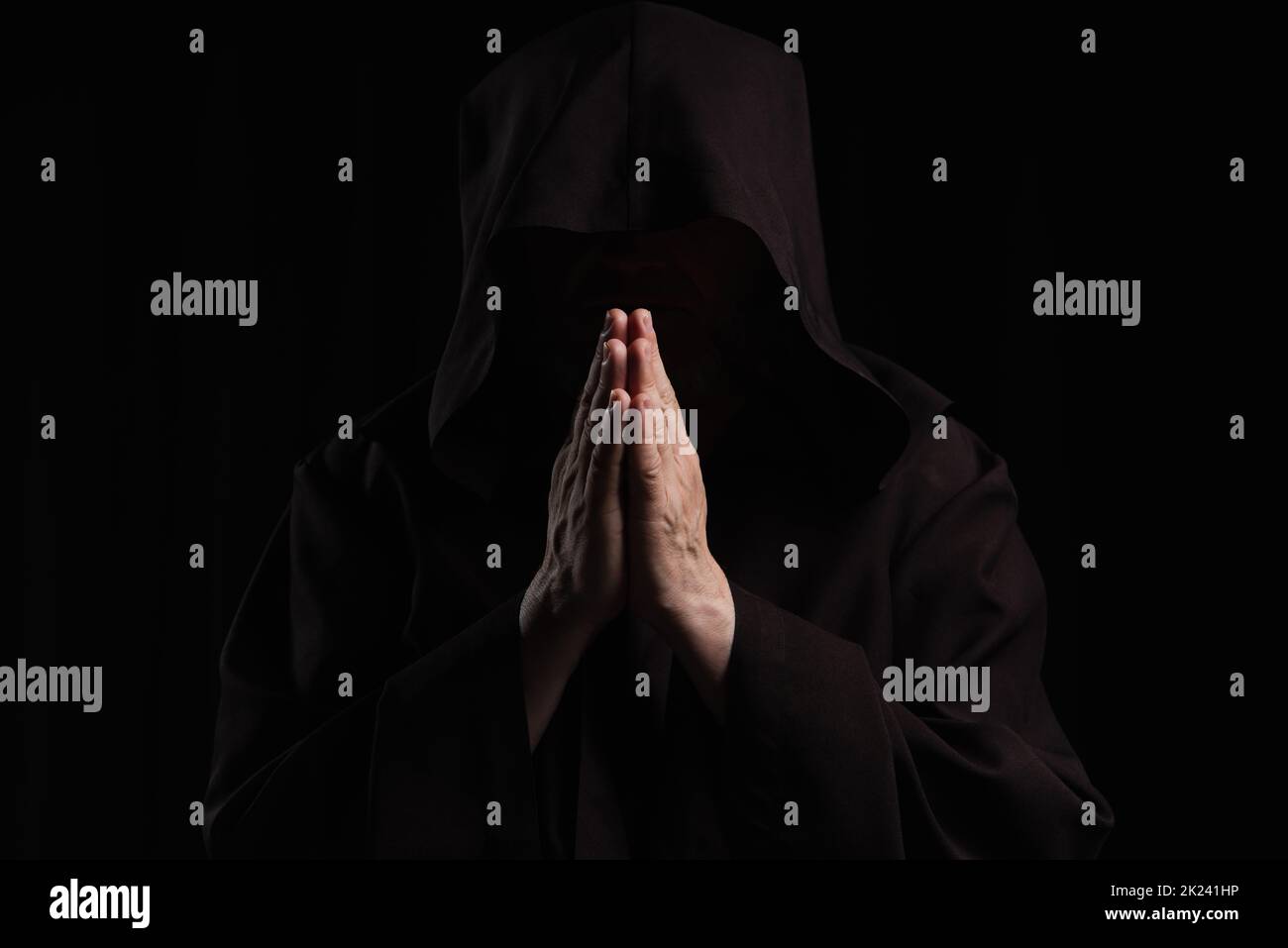 front view of mysterious anonymous monk with praying hands isolated on ...
