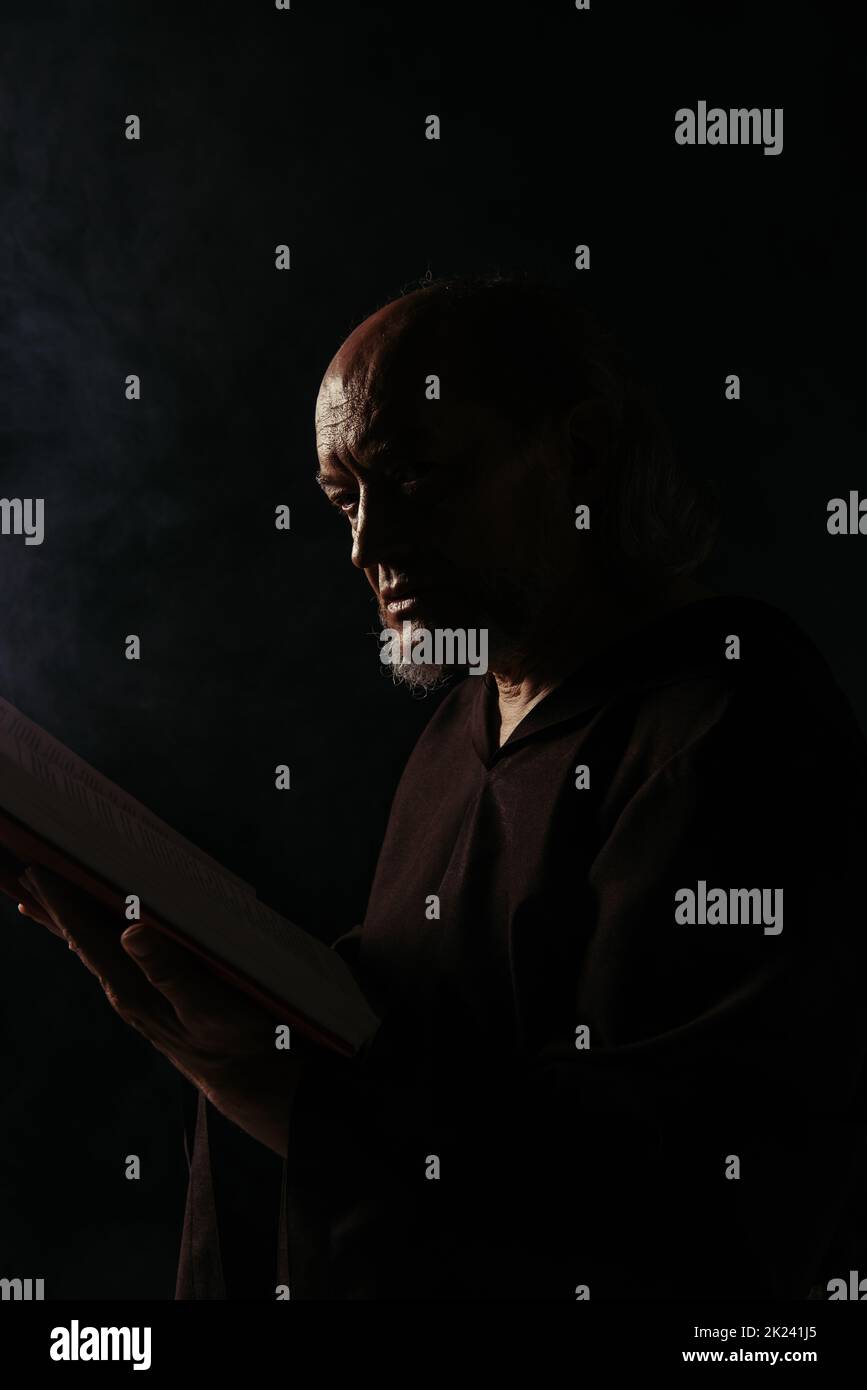 senior medieval monk reading holy bible in darkness isolated on black ...
