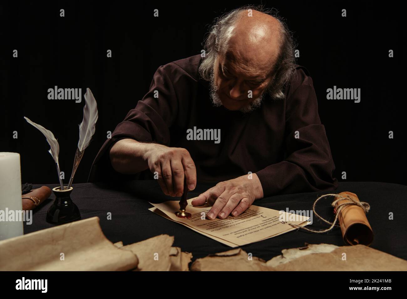 senior monk stamping manuscript with wax seal near parchments isolated ...