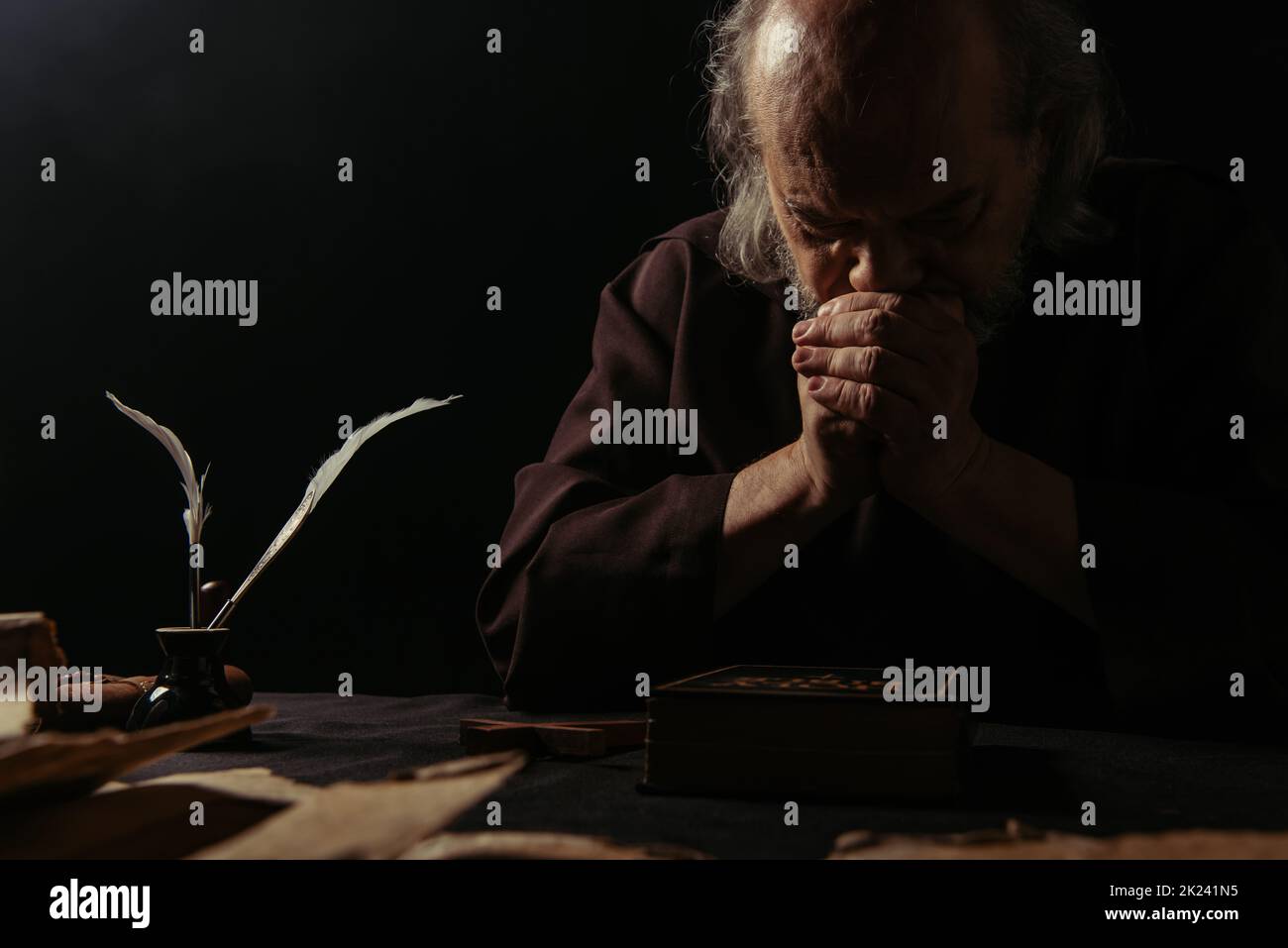 medieval monk praying at night near cross and holy bible isolated on ...