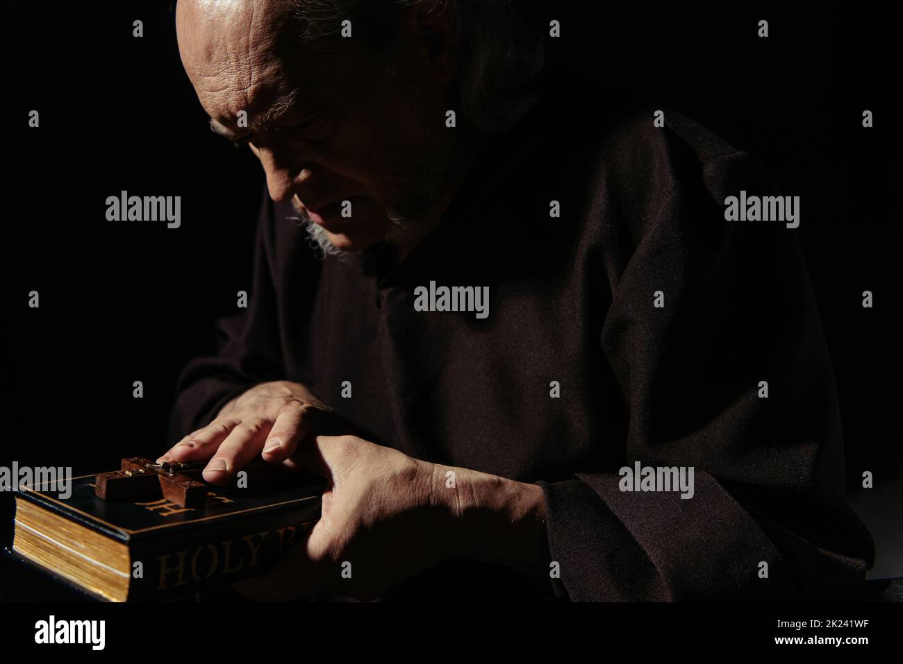monk in dark robe holding bible and crucifix isolated on black,stock ...