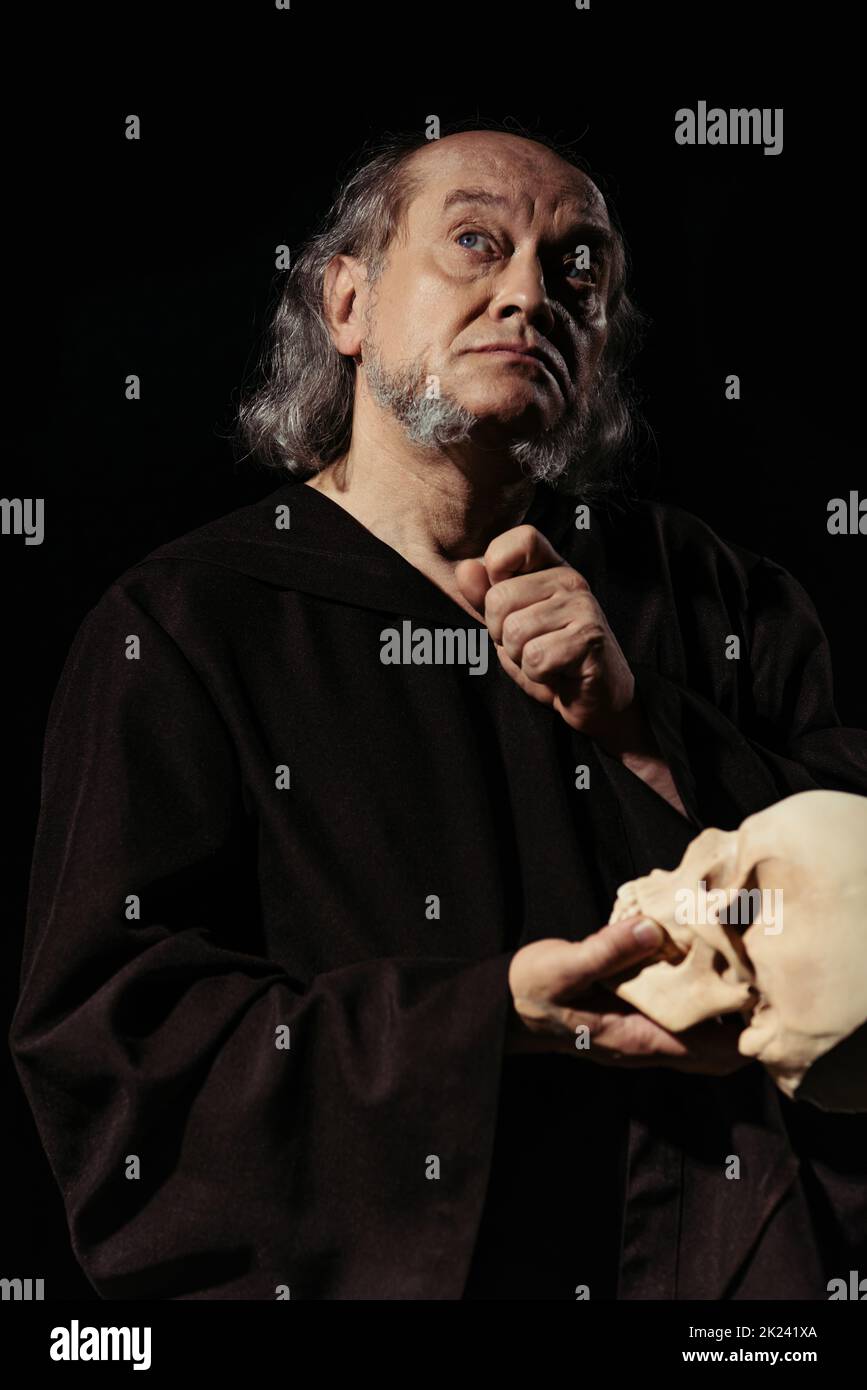 medieval religious philosopher with skull looking up while thinking ...