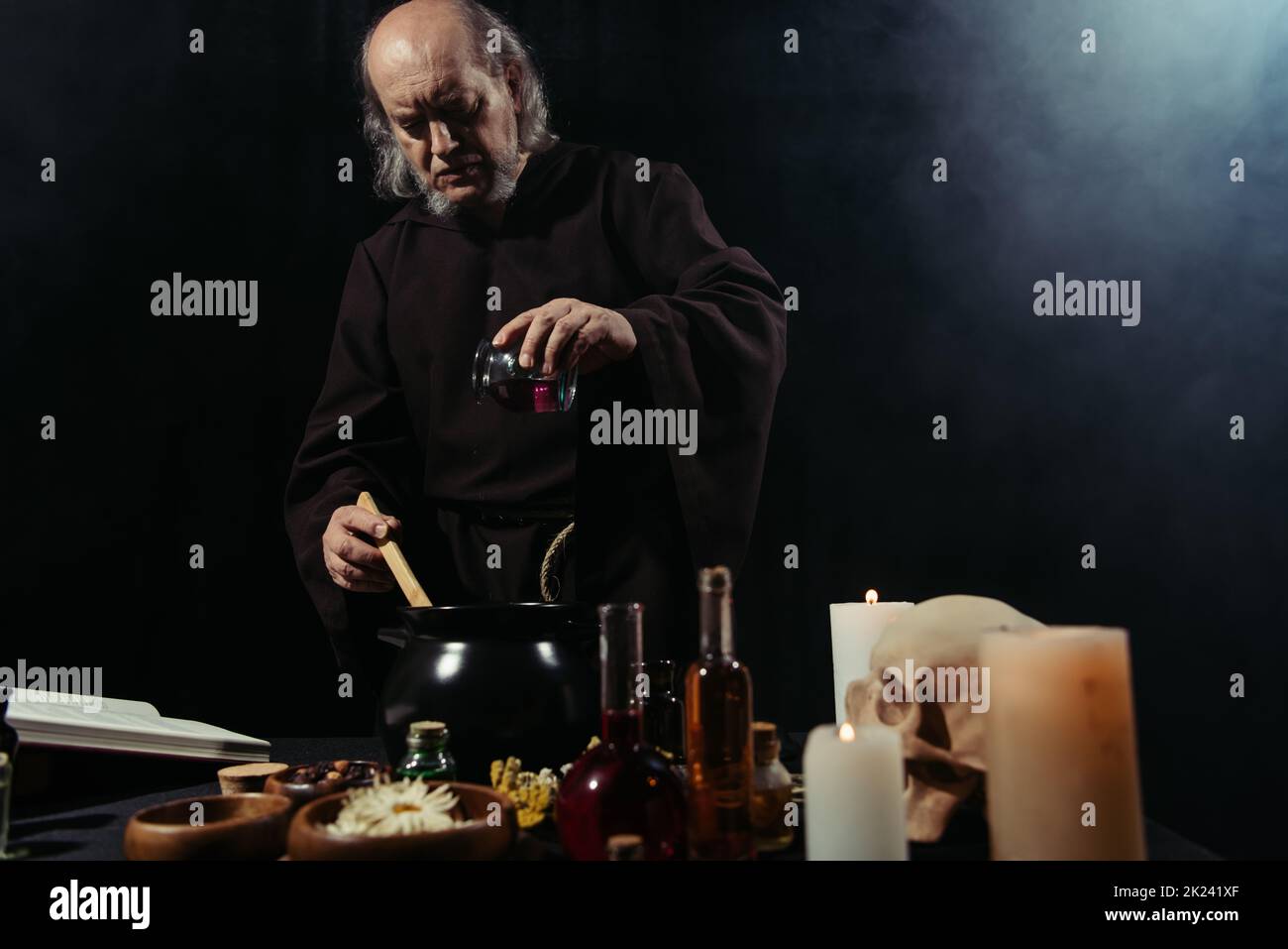 mysterious alchemist adding ingredient into pot while cooking in dark ...