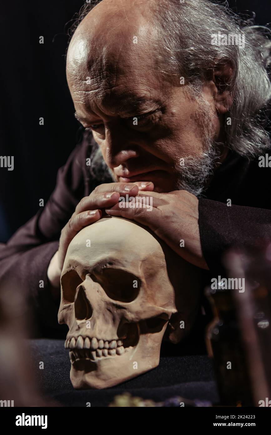 senior medieval philosopher leaning on skull while thinking isolated on ...