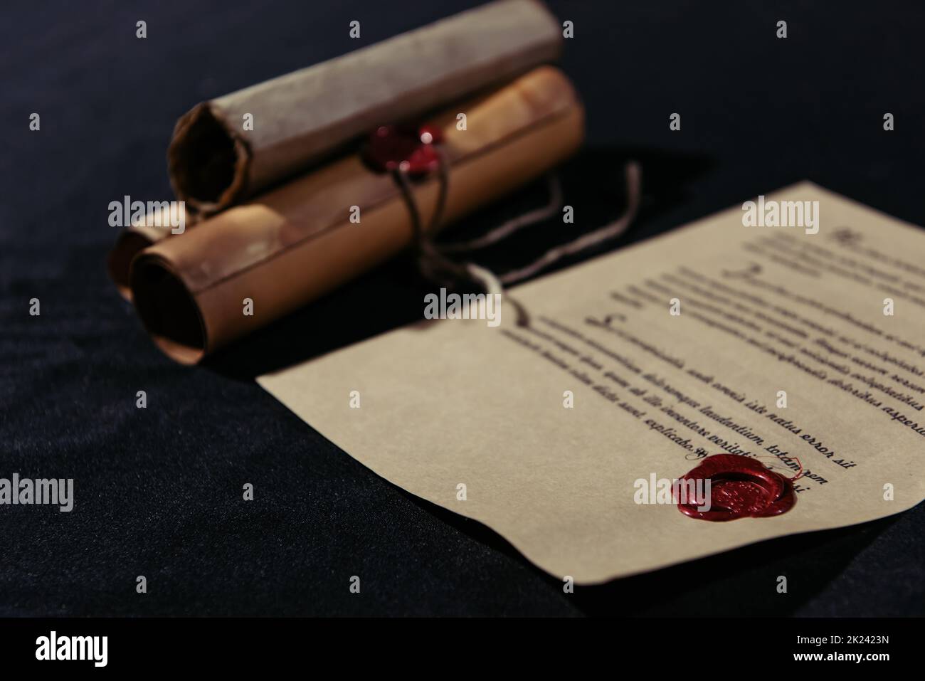 old manuscript stamped with wax seal near rolled parchments on black ...