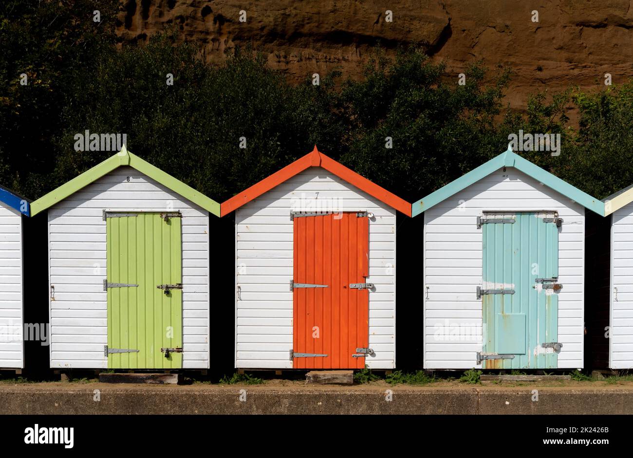 Bright coloured beach huts standing out from the dark coloured ...