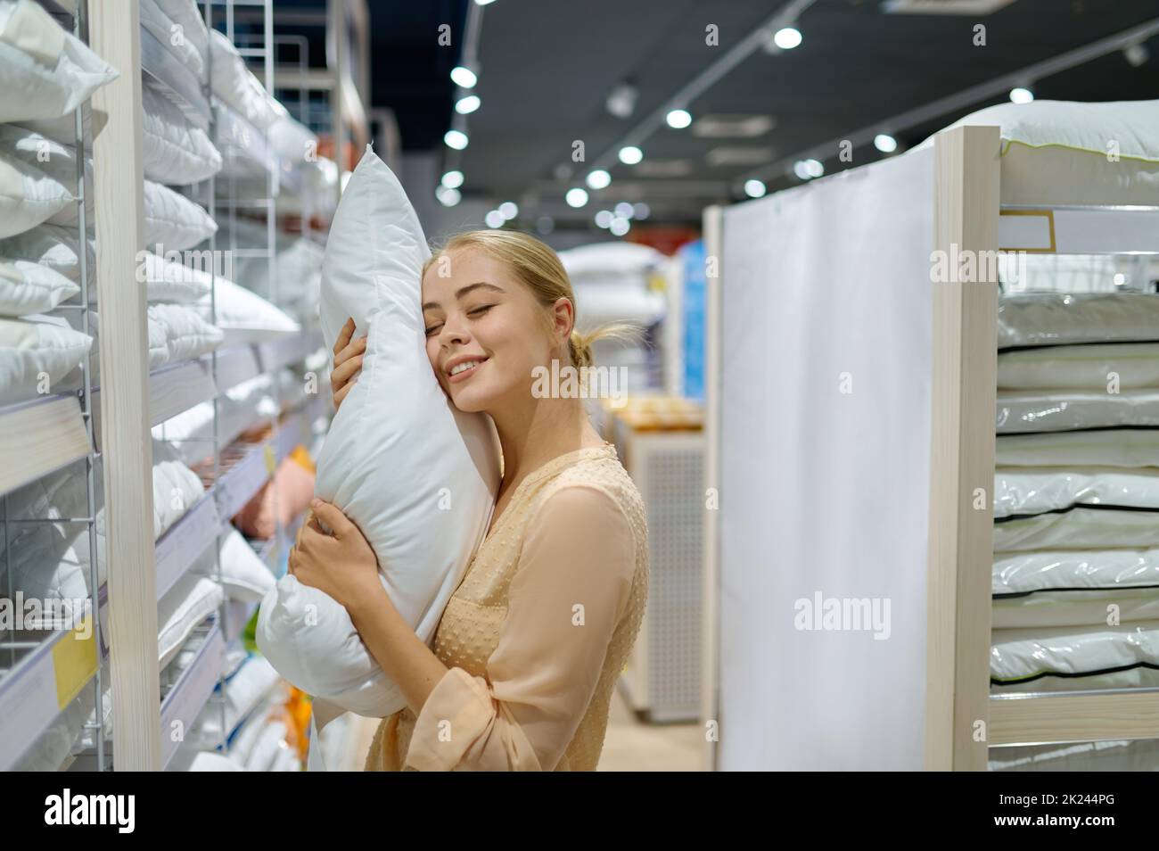 Smiling satisfied woman customer holding downy pillow buying goods in ...