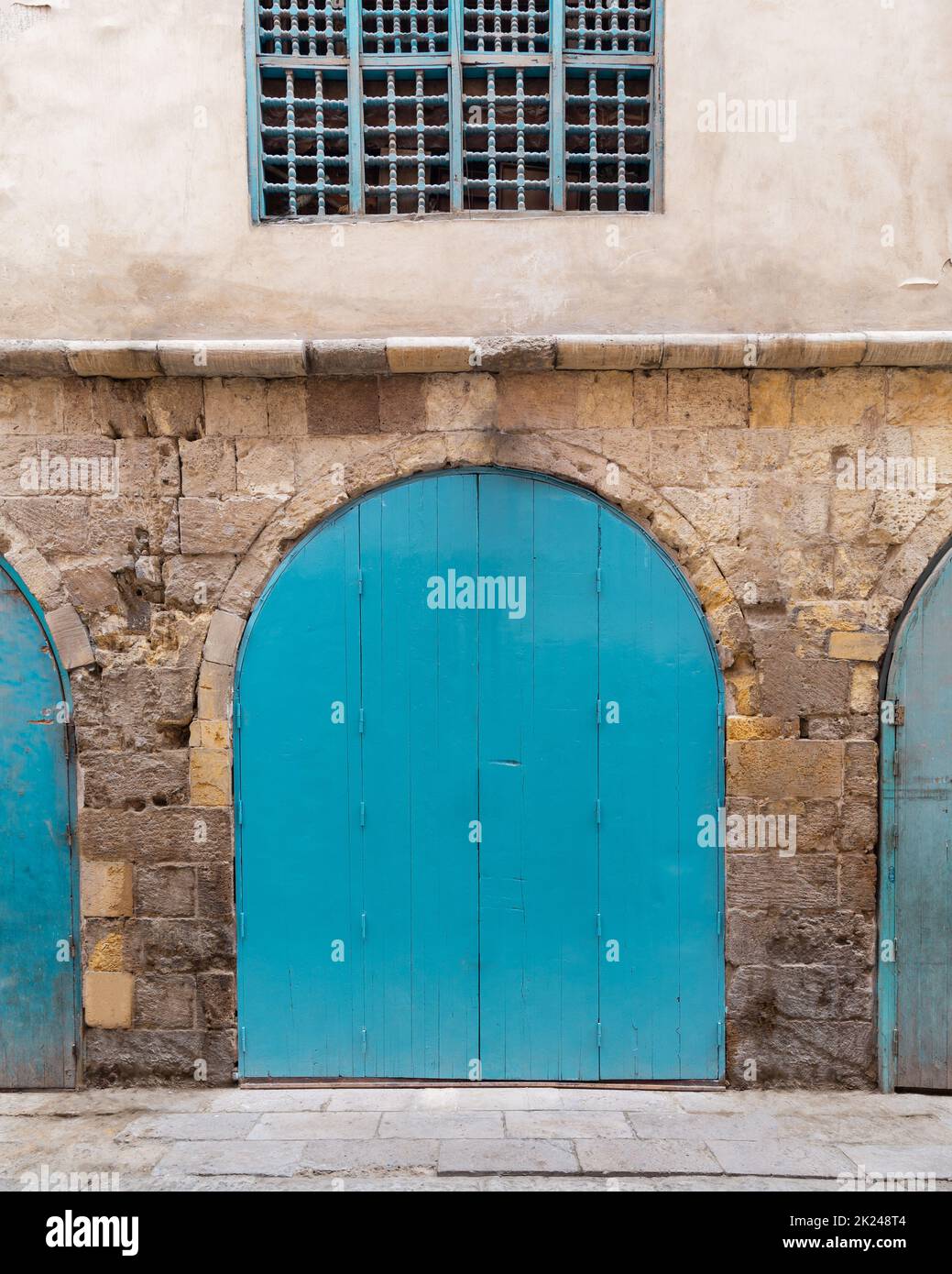 Closed turquoise weathered wooden arched door and wood window grill in ...