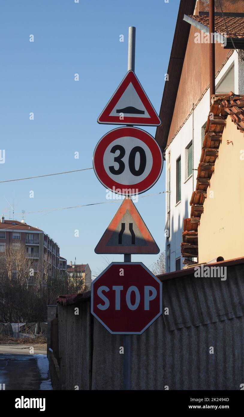 pole with many traffic signs including uneven road, speed limit, road ...