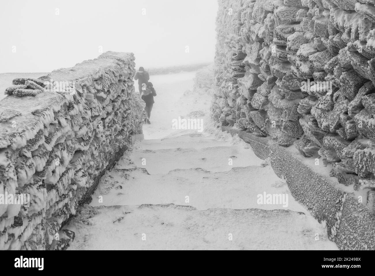 Stone fence and stone wall covered with ice and snow. Tourists in a ... Stone fence and stone wall covered with ice and snow. Tourists in a ...