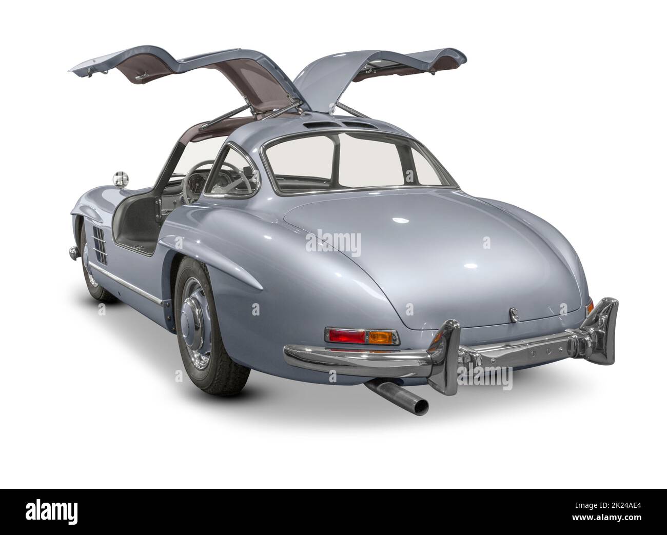 Silver colored historic vehicle with open gull-wing doors in white back ...