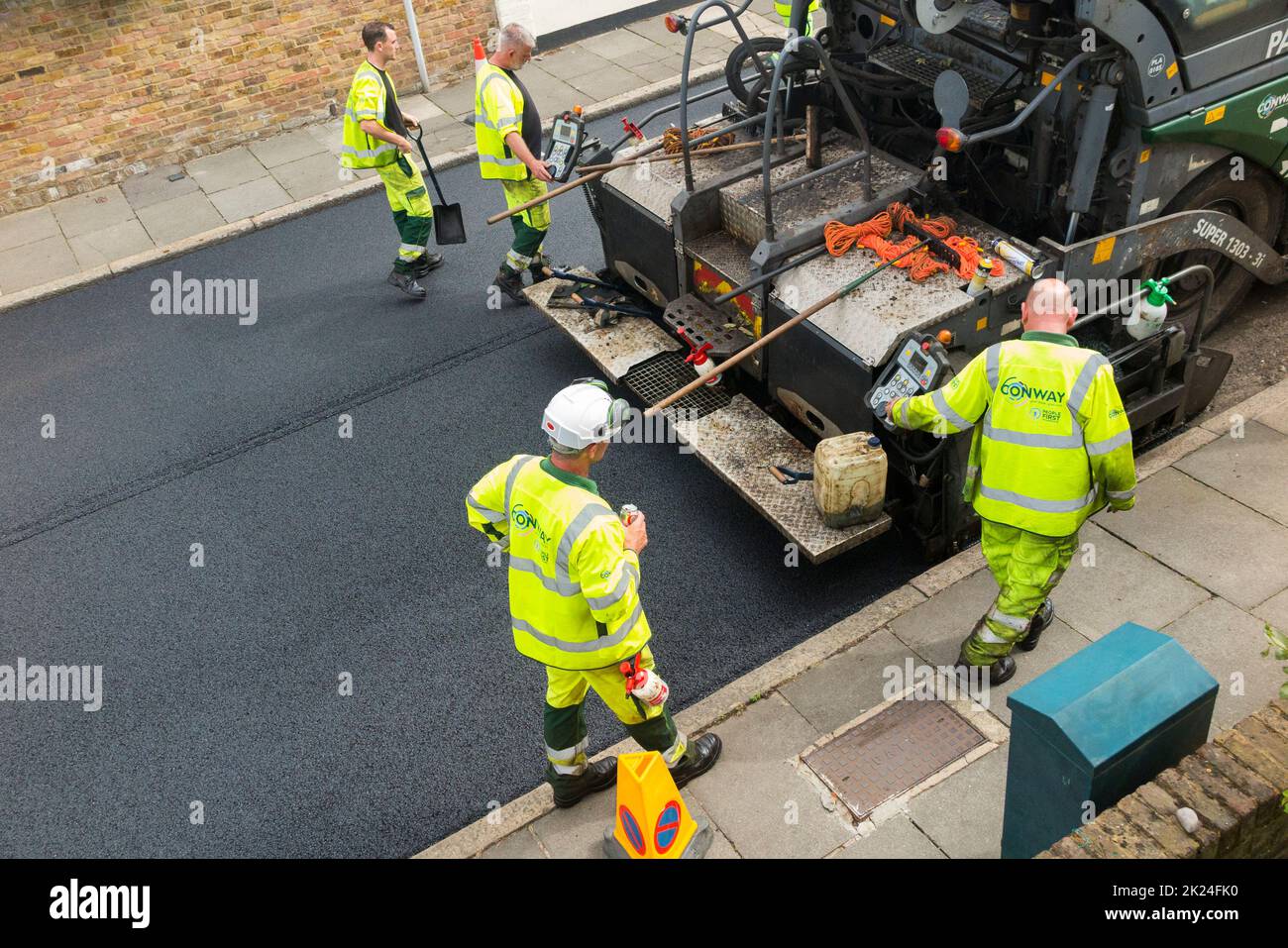 Hot tarmacadam being spread by an asphalt tarmac paver machine during ...