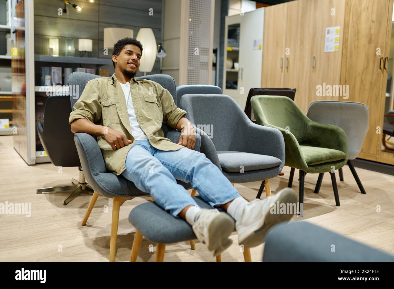 Man testing chair sitting on it. Furniture store shop interior with ...