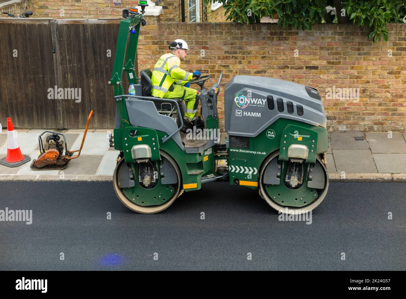 Road roller smoothing hot tarmac that has been laid while resurfacing a ...