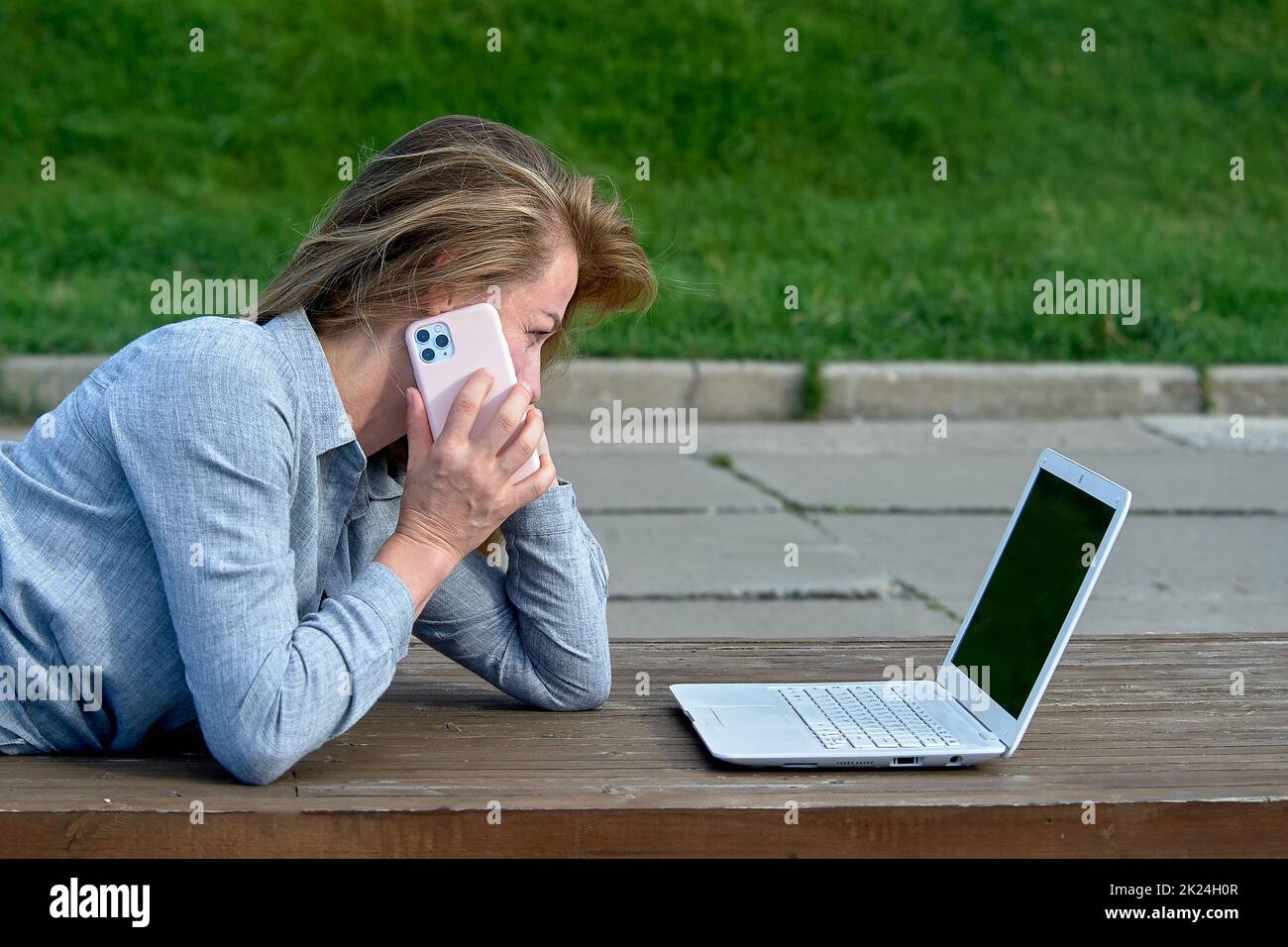A woman with a laptop sits on a wooden platform, works online. High ...