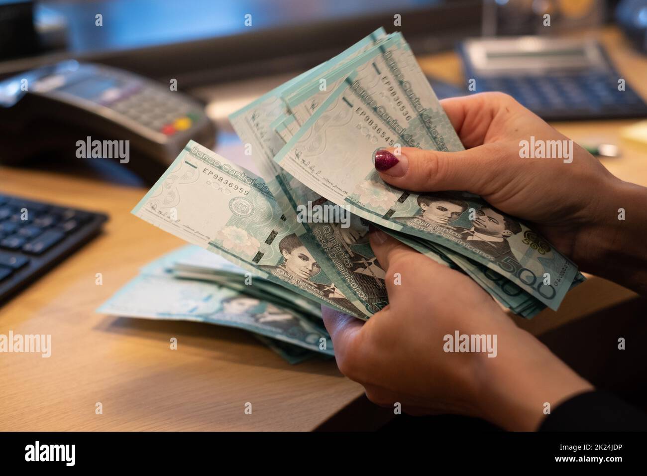 Cashier counting Dominican Republic 500 peso bank notes on wooden table ...