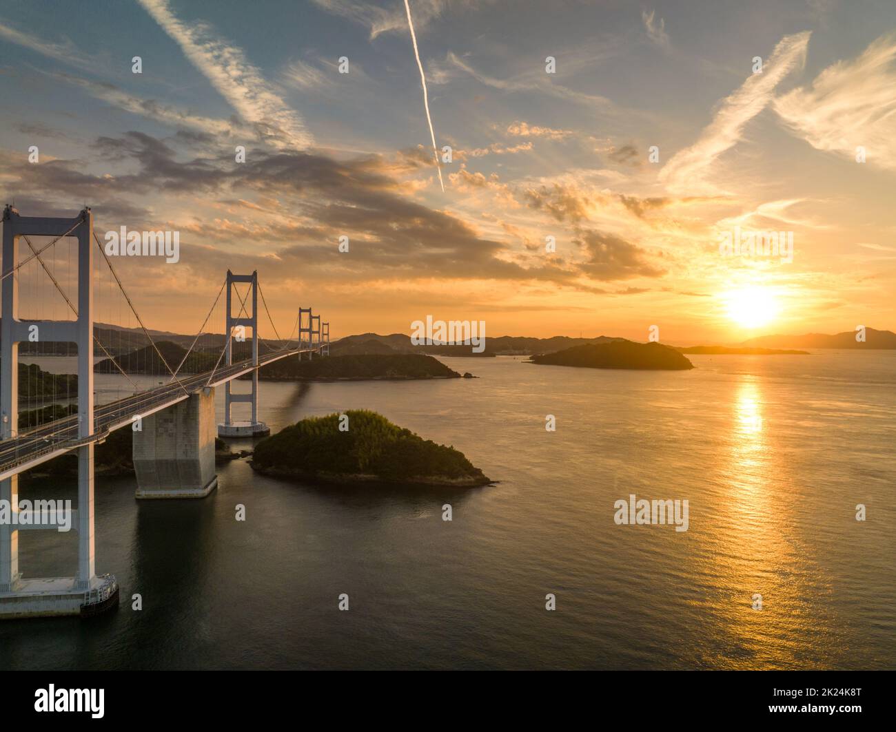 Beautiful sunset next to long suspension bridge between small islands ...