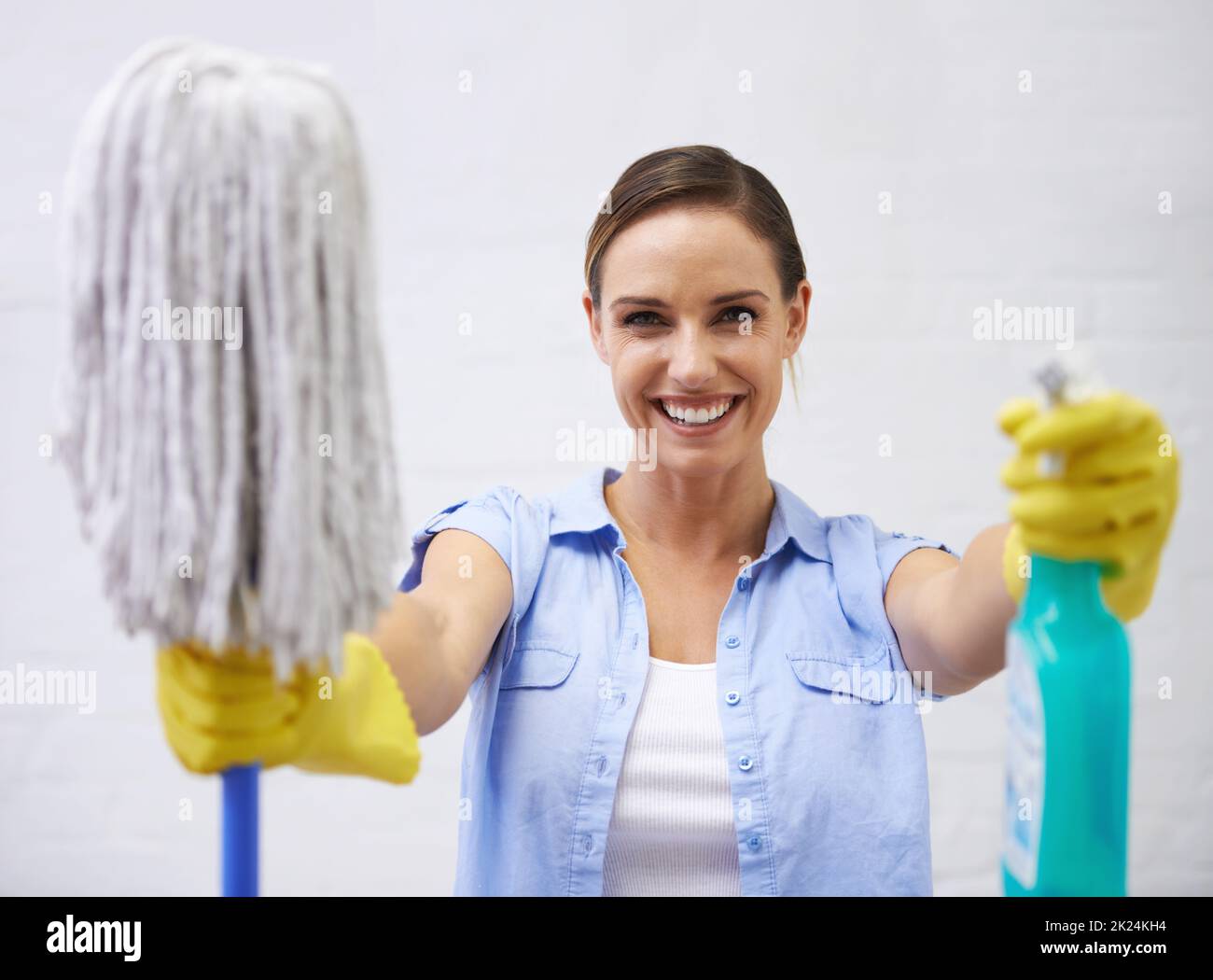 Lets get your hands dirty. a smiling woman holding out a mop and spray ...