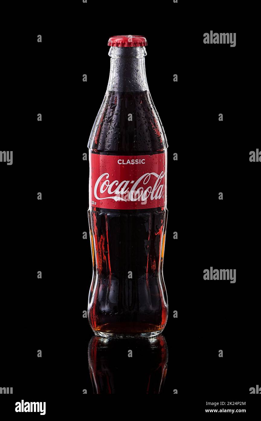 Glass bottle of Coca Cola on a black background with water drops on the ...