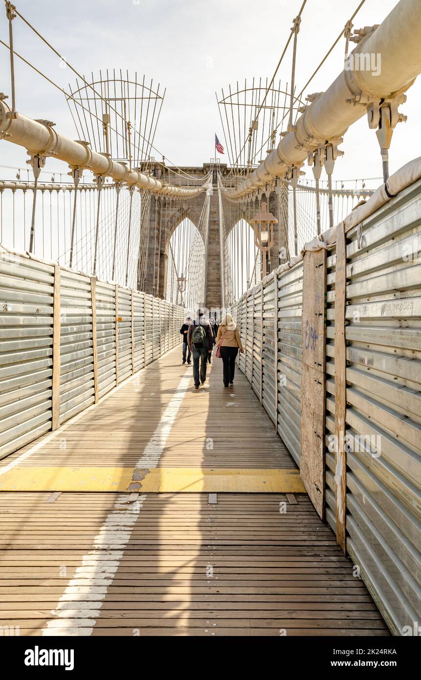 People walking on Brooklyn Bridge during sunset, New York City, rear ...