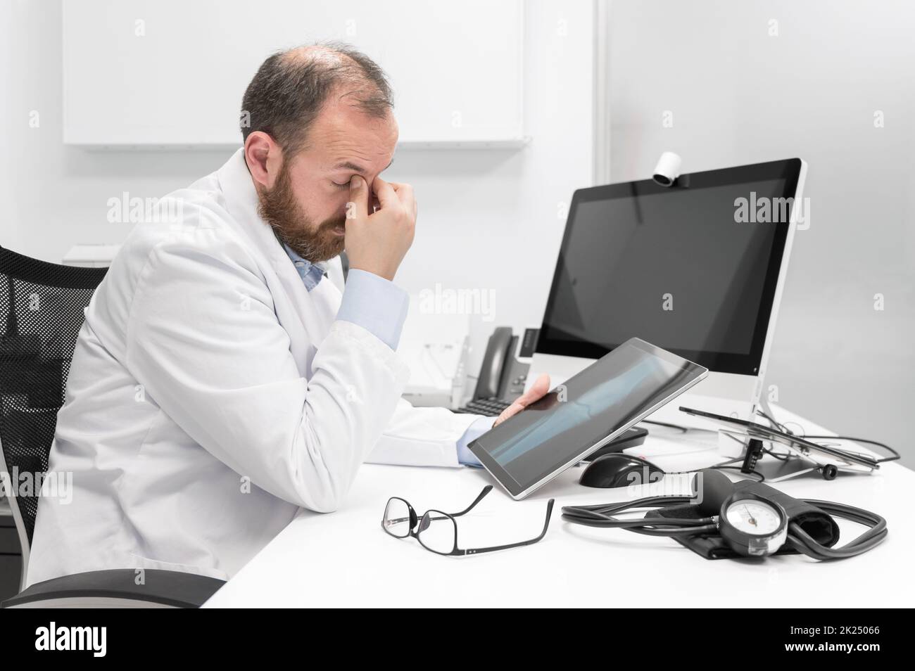 Young doctor rubbing his eyes, feeling tired and unhappy. Health care ...