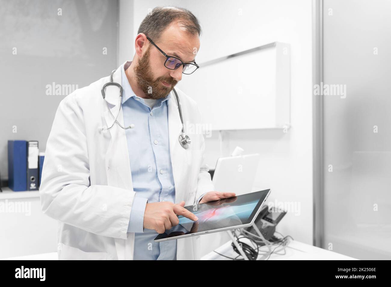 Doctor examine an x-ray image of a patient in digital tablet at doctor ...