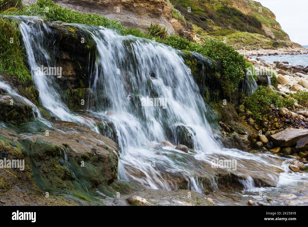 A small waterfall on the beach at Osmington Mills, a coastal village in ...