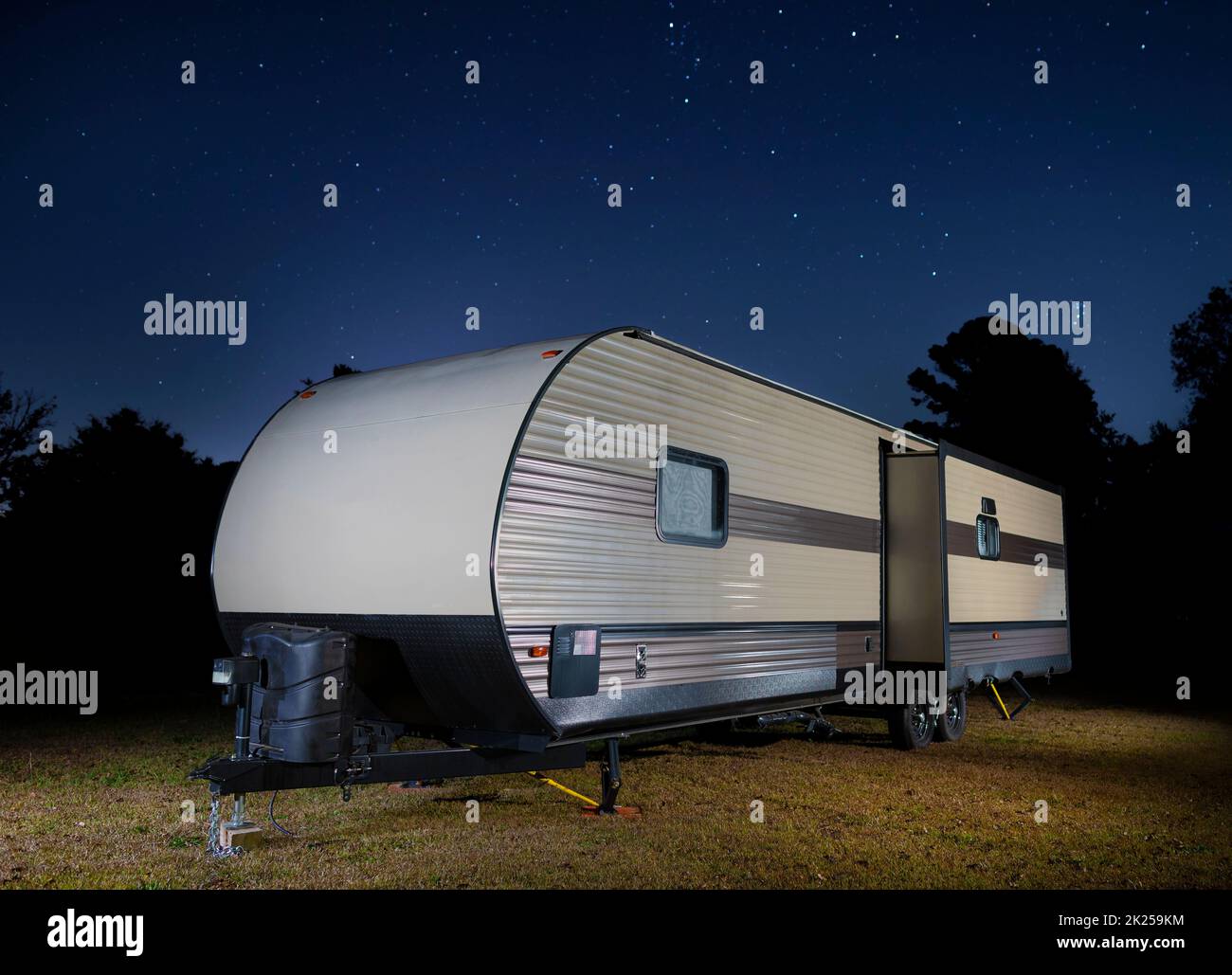 Travel trailer on a grassy field with bright stars above at night Stock ...
