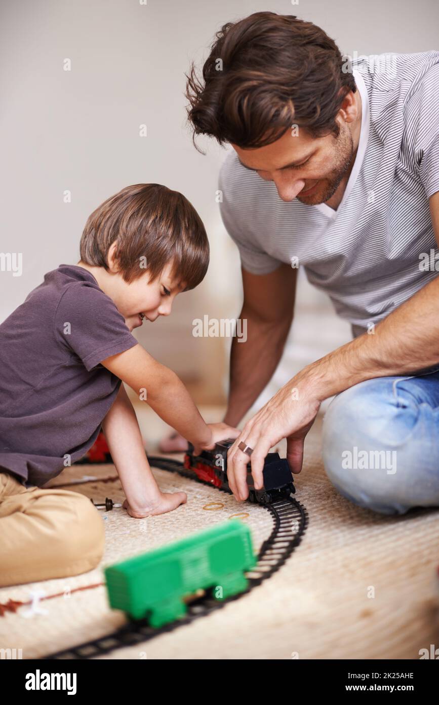 Fun with dad on the railroad. a father and son playing with a toy train ...
