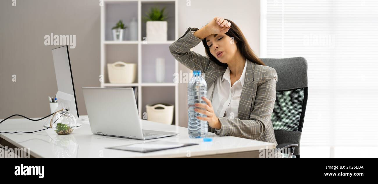 Thirsty Person Working At Desk With Bottle Stock Photo - Alamy
