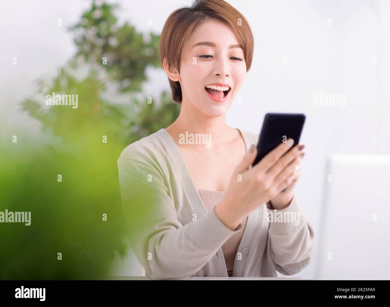 Beautiful excited young woman watching mobile phone in living room ...