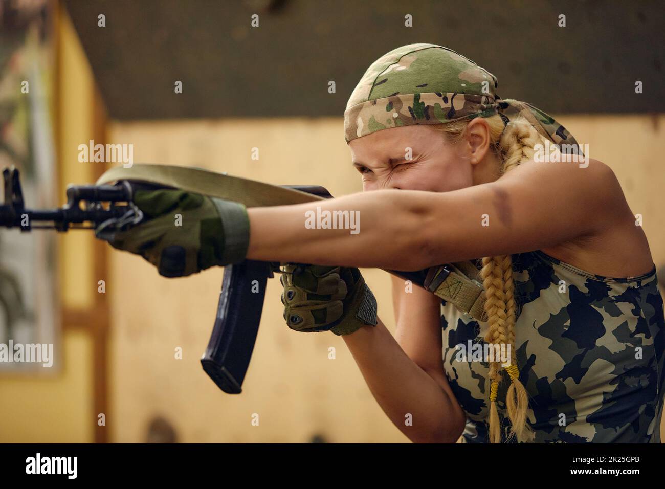 Young beautiful military woman holding rifle and take aim. Ready to ...