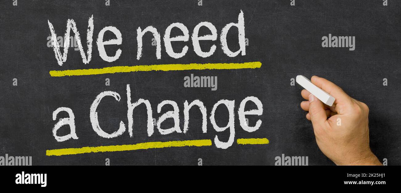 Text written on a blackboard - We need a change Stock Photo - Alamy