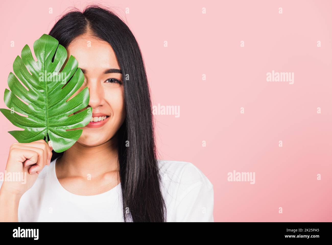 woman with fresh healthy skin hold green monstera leaf on her face ...