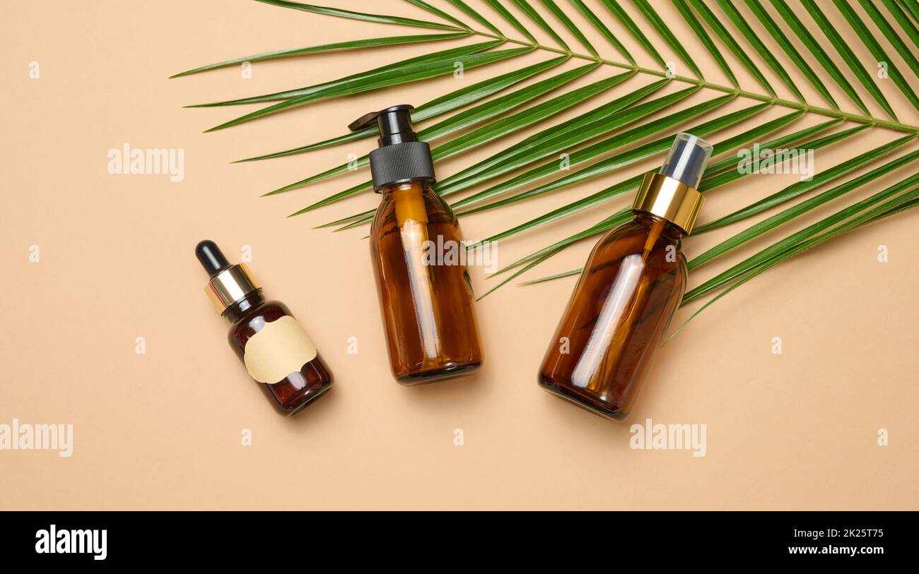 glass brown cosmetic bottles with pipette, spray and dispenser on brown ...