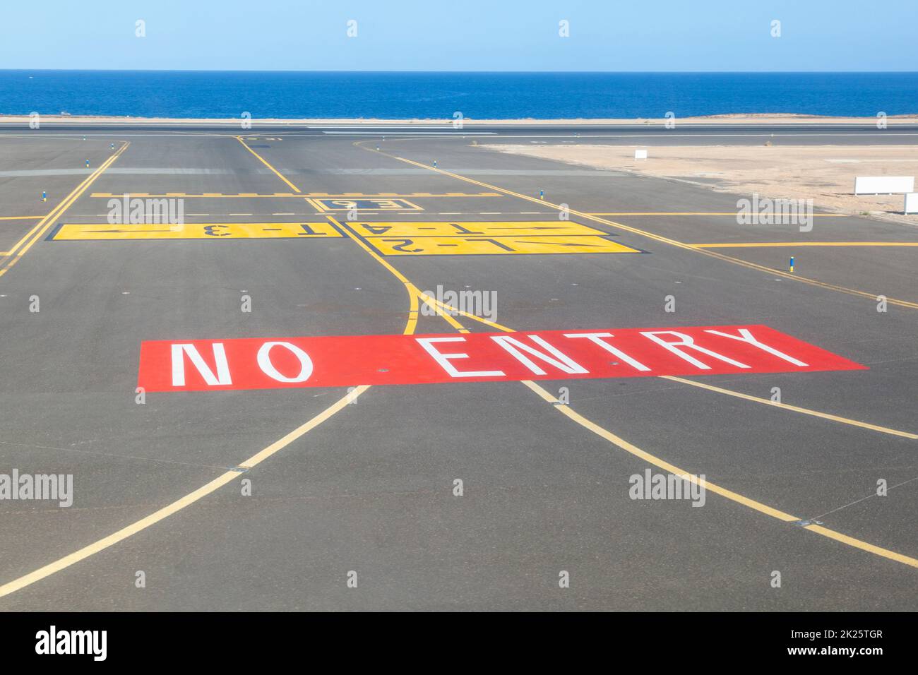 no entry sign at the runway of the airport with ocean in background ...