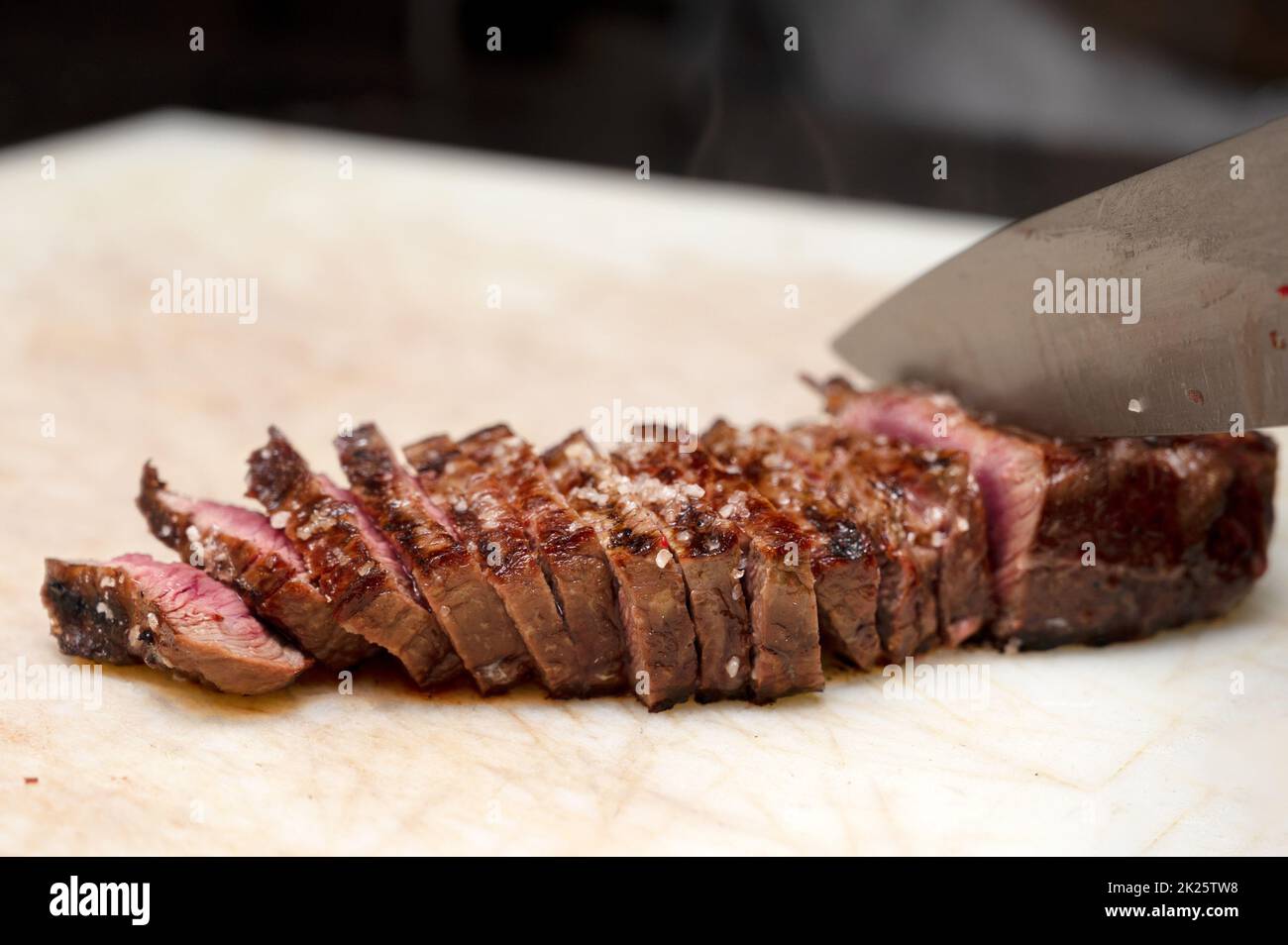 Chef cutting juicy steak on a board at commercial kitchen Stock Photo ...