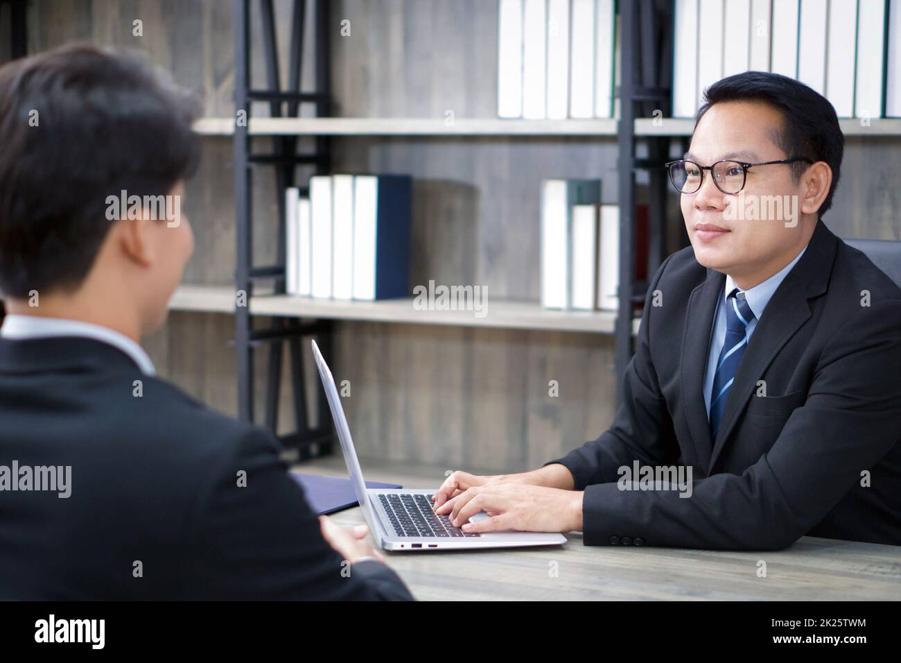 Asian manager in black suit interview the applicant with a smile. The ...