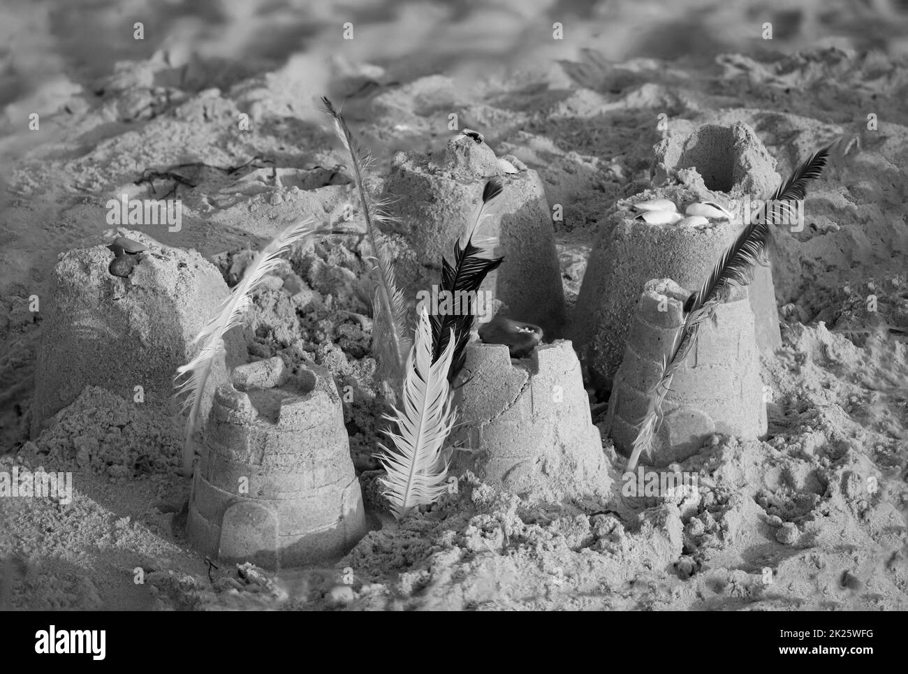 A round large sand castle decorated with feathers on the beach of the ...