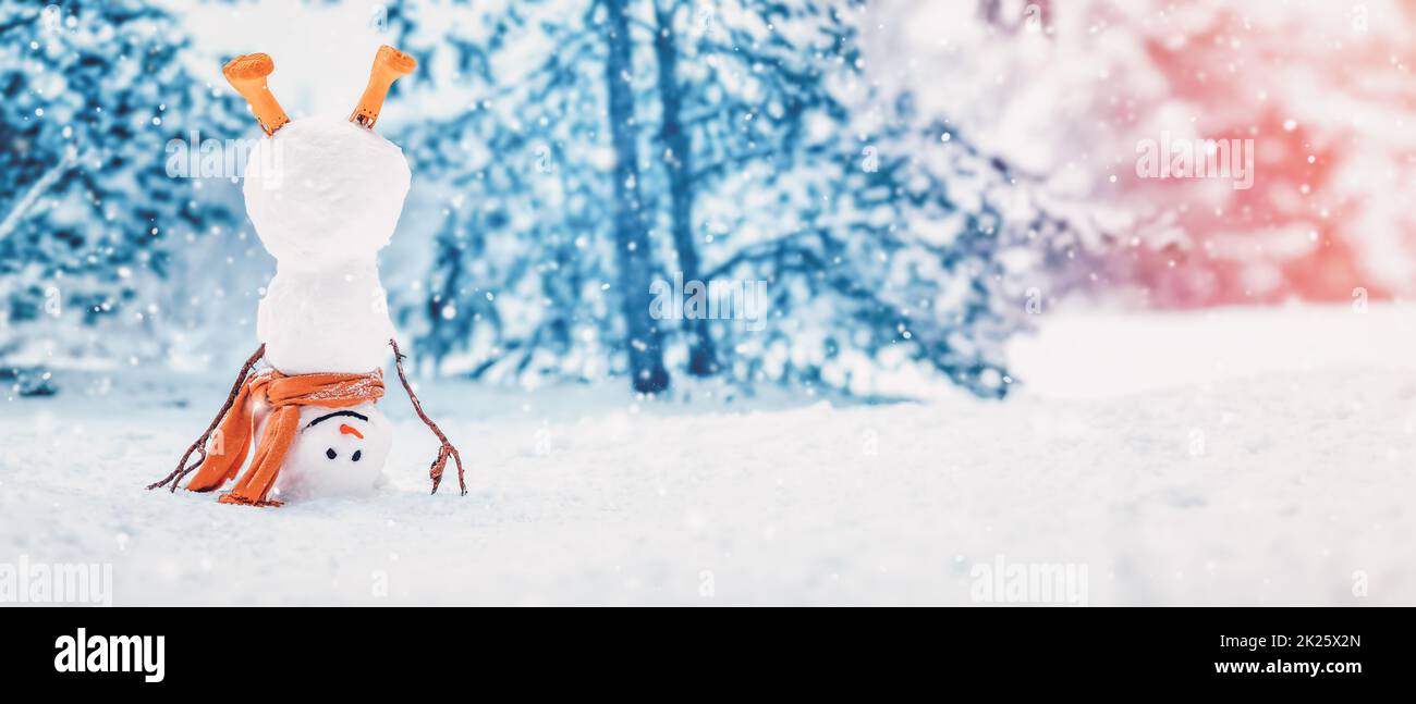 Cheerful snowman with orange scarf and in yellow boots stands upside ...
