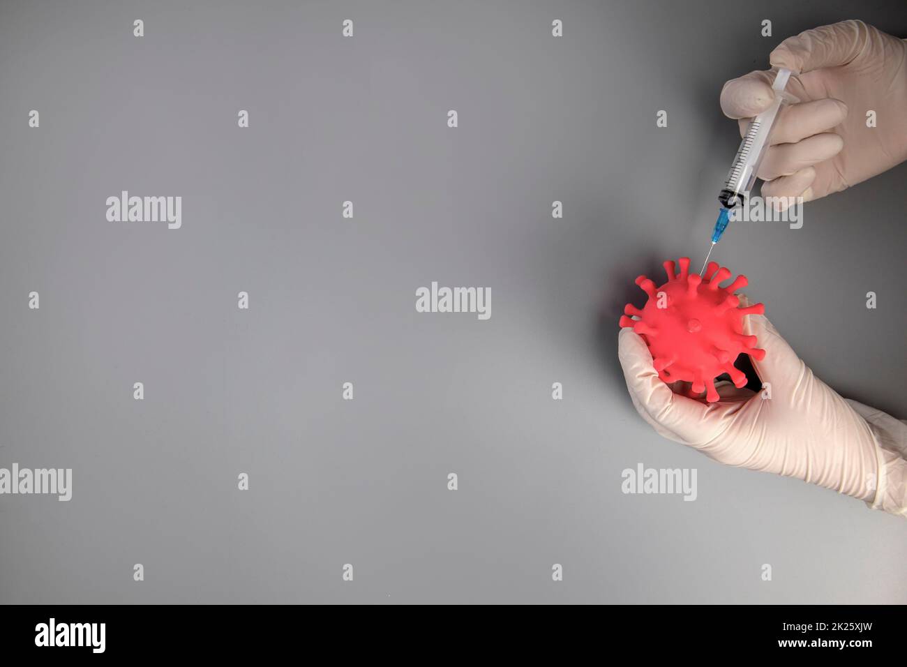 Hand in white glove holding syringe on grey background with copy space. gives injection in virus ...