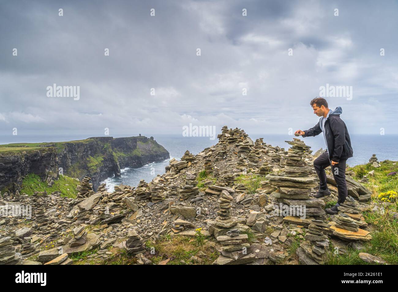 Man stone stacking in iconic Cliffs of Moher, Ireland Stock Photo - Alamy