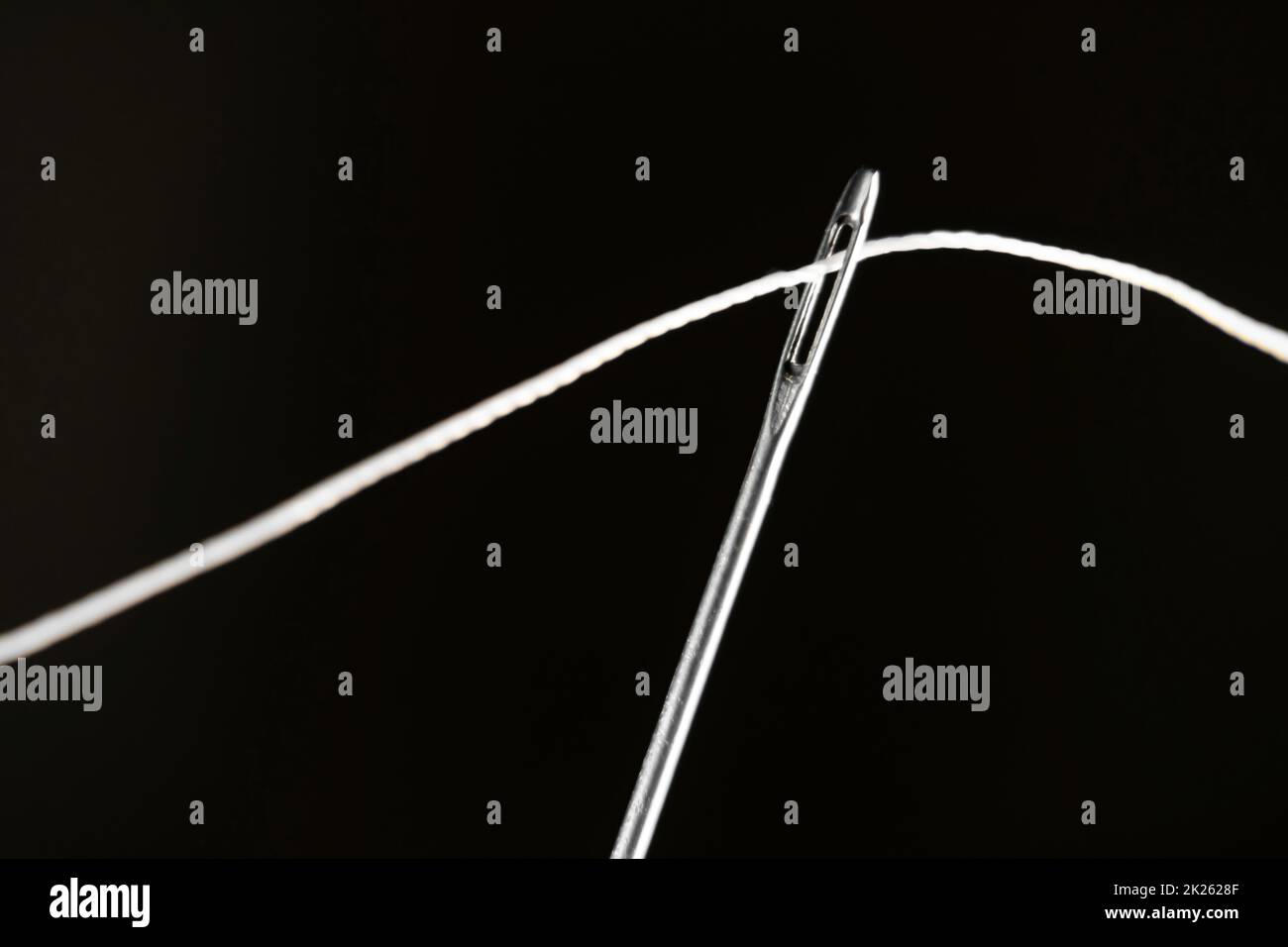 The thread is threaded through the eye of a sewing needle. Sewing and ...