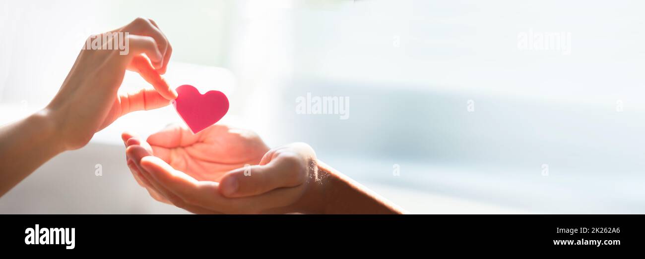 Woman Giving Heart On Man's Hand Stock Photo - Alamy