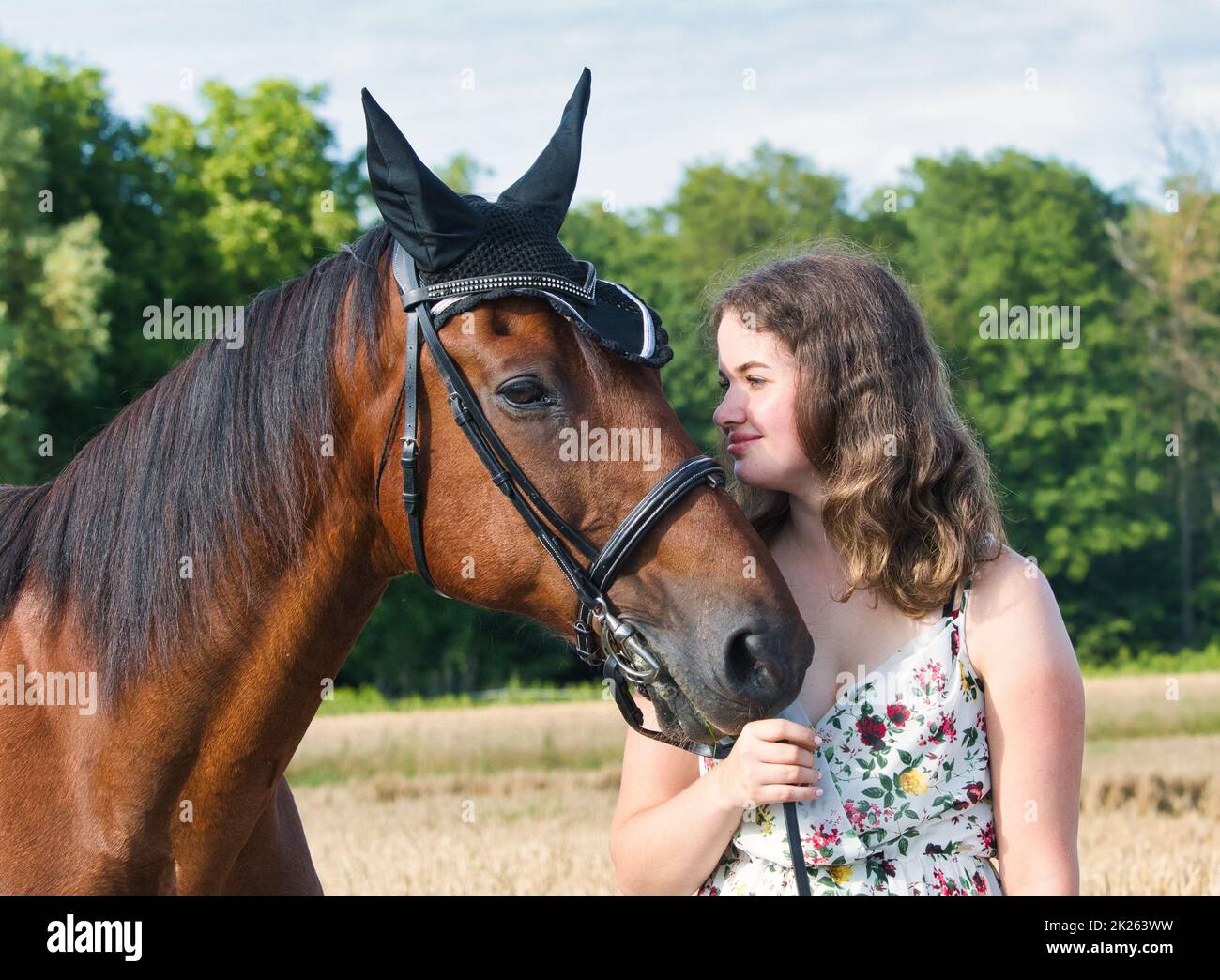 Portrait of a smiling caucasian teenage girl in a dress, holding a bay ...