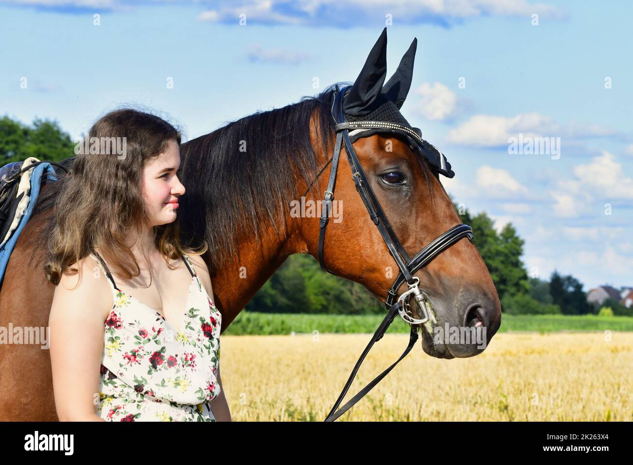 Portrait of a smiling caucasian teenage girl in a dress, holding a bay ...