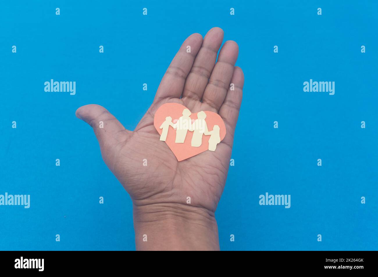 Happy paper family on a man hand with palm facing upwards against blue ...
